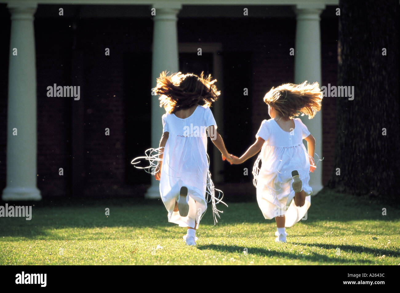 TWO YOUNG GIRLS IN WHITE DRESSES RUNNING HAND IN HAND Stock Photo - Alamy