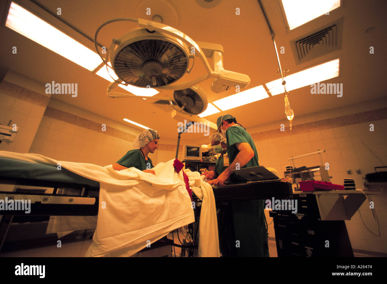 LOW ANGLE VIEW OF THREE SURGEONS PERFORMING A HERNIA OPERATION ON A ...