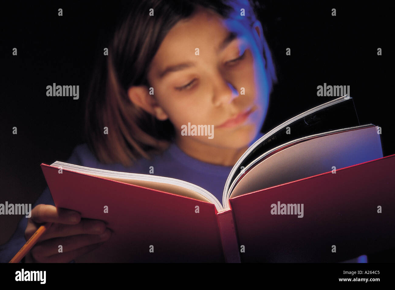 CHILD READING IN A BOOK HOLDING A PENCIL Stock Photo - Alamy