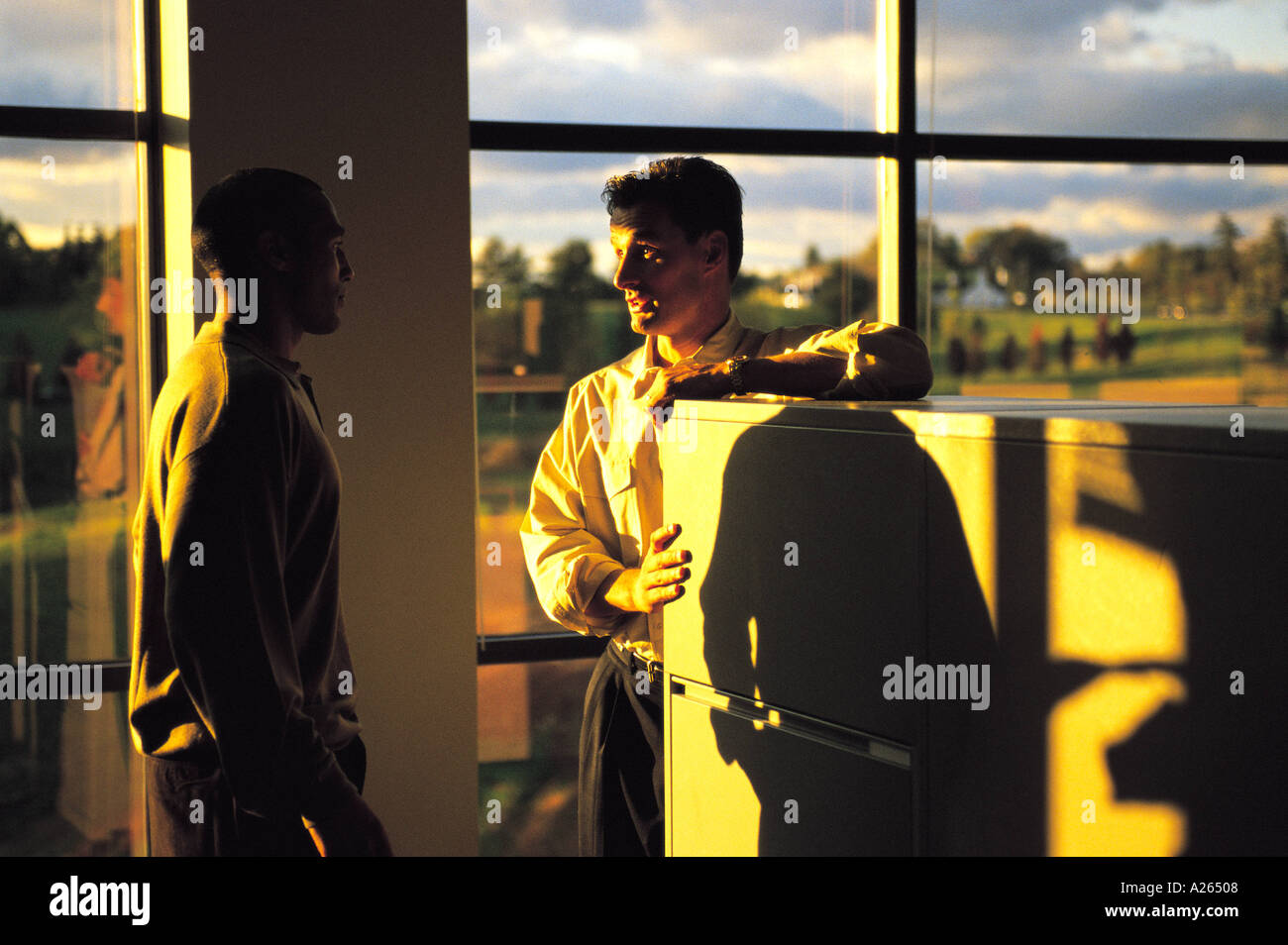 TWO MEN STANDING TALKING IN SUNLIGHT AND SHADOWS Stock Photo - Alamy