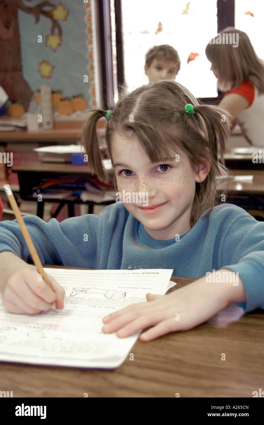Smiling 3rd grade elementary student working on a project at their desk ...