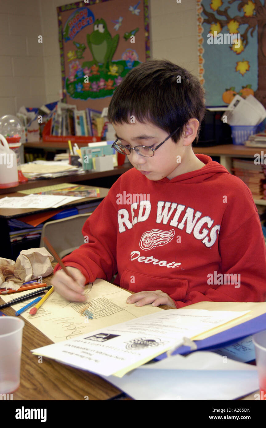 Smiling 3rd grade elementary student working on a project at their desk ...