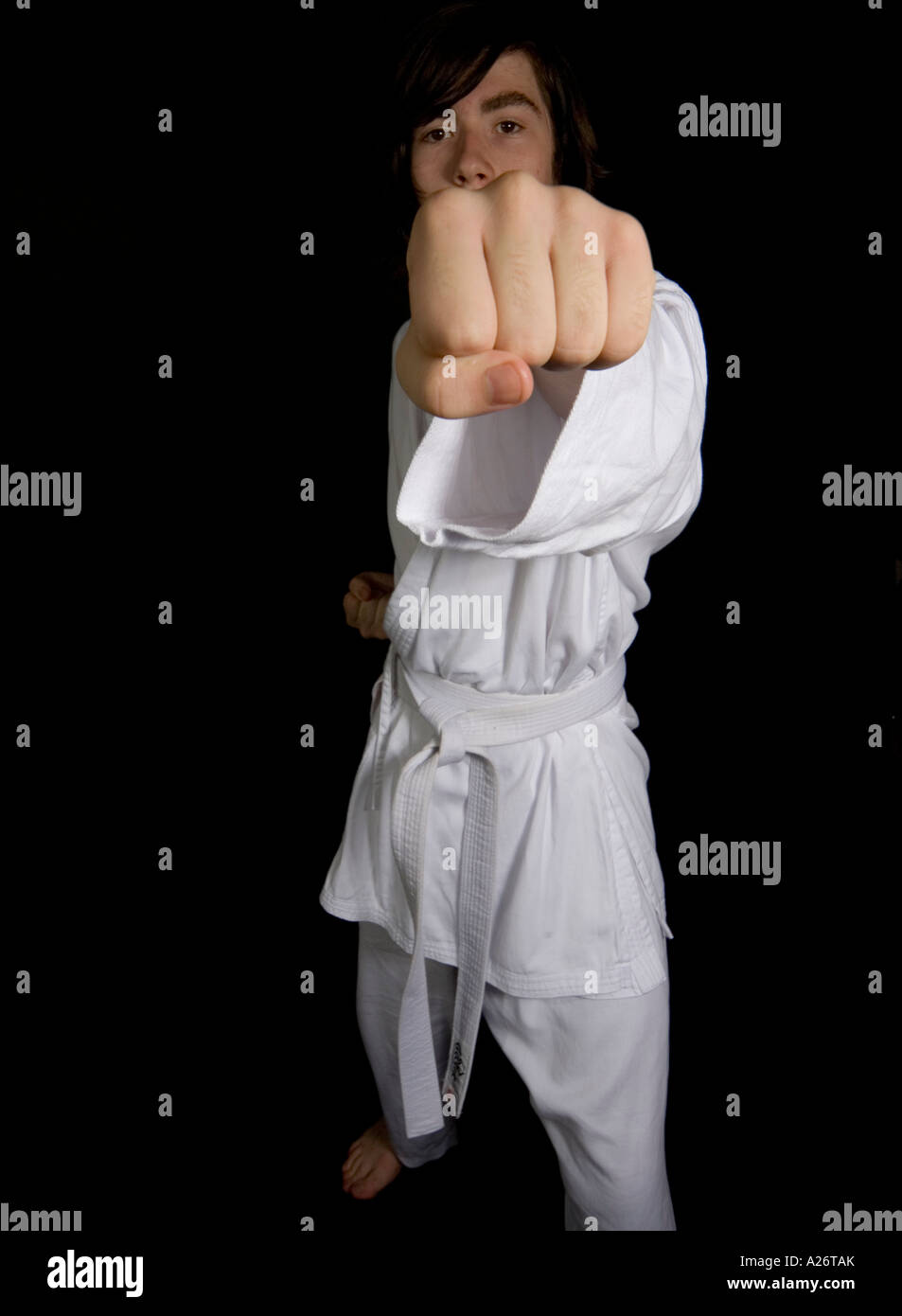 Young man in martial arts uniform in attacking position with fist ...
