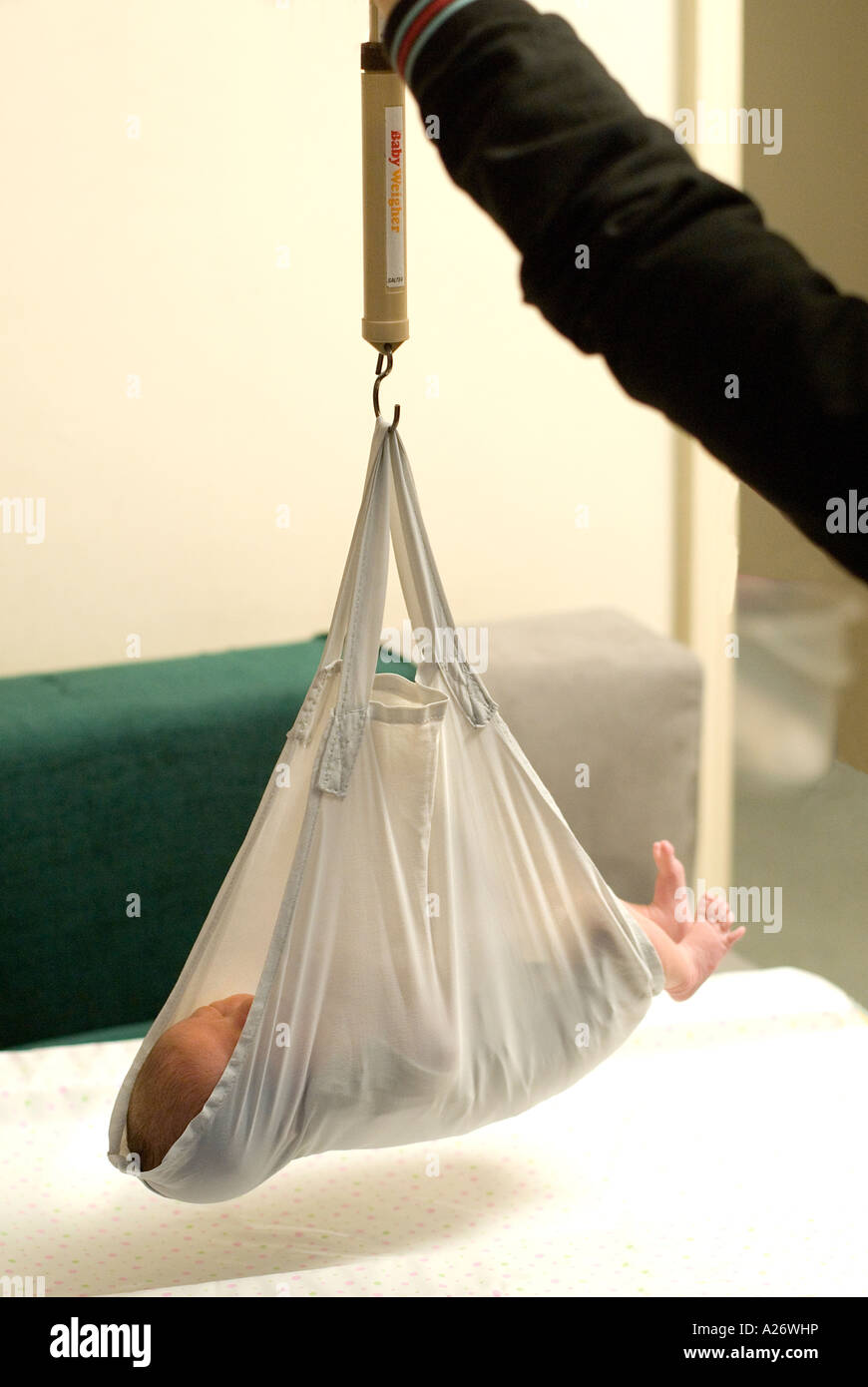 Community midwife making a home visit and weighing a newborn baby on a ...