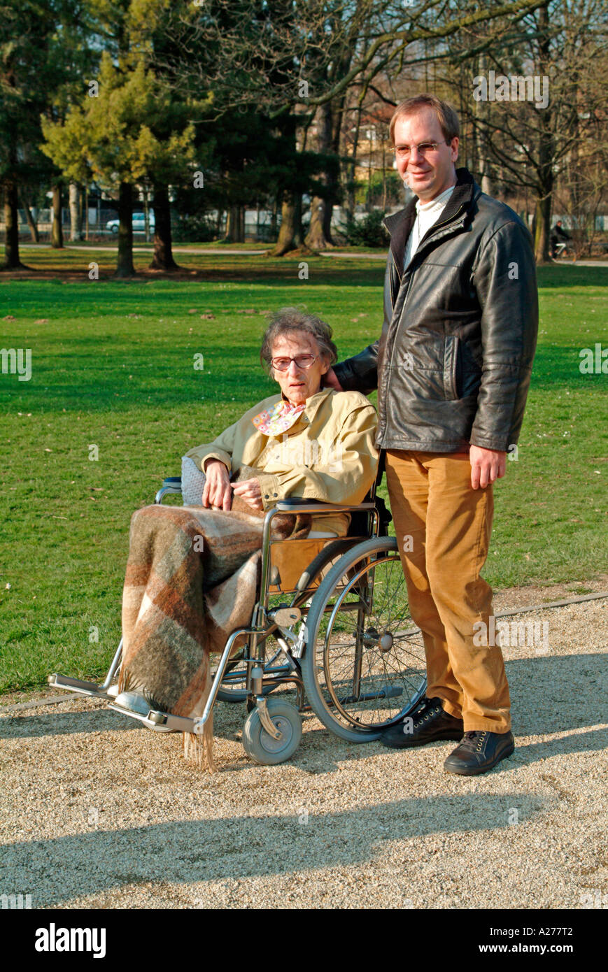 MR young man pushing a wheel chair wheelchair with an old woman in a ...