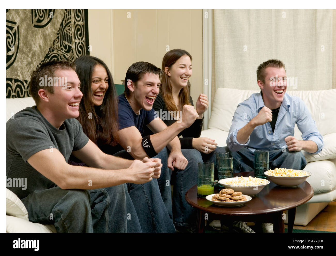 College students watching a game on television while munching on ...