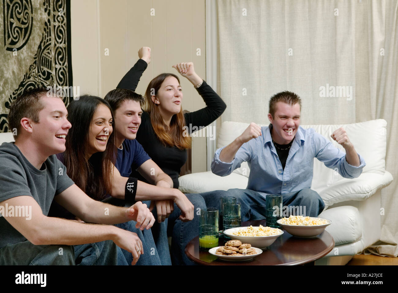 College roommates watching a game on television and rooting Stock Photo ...