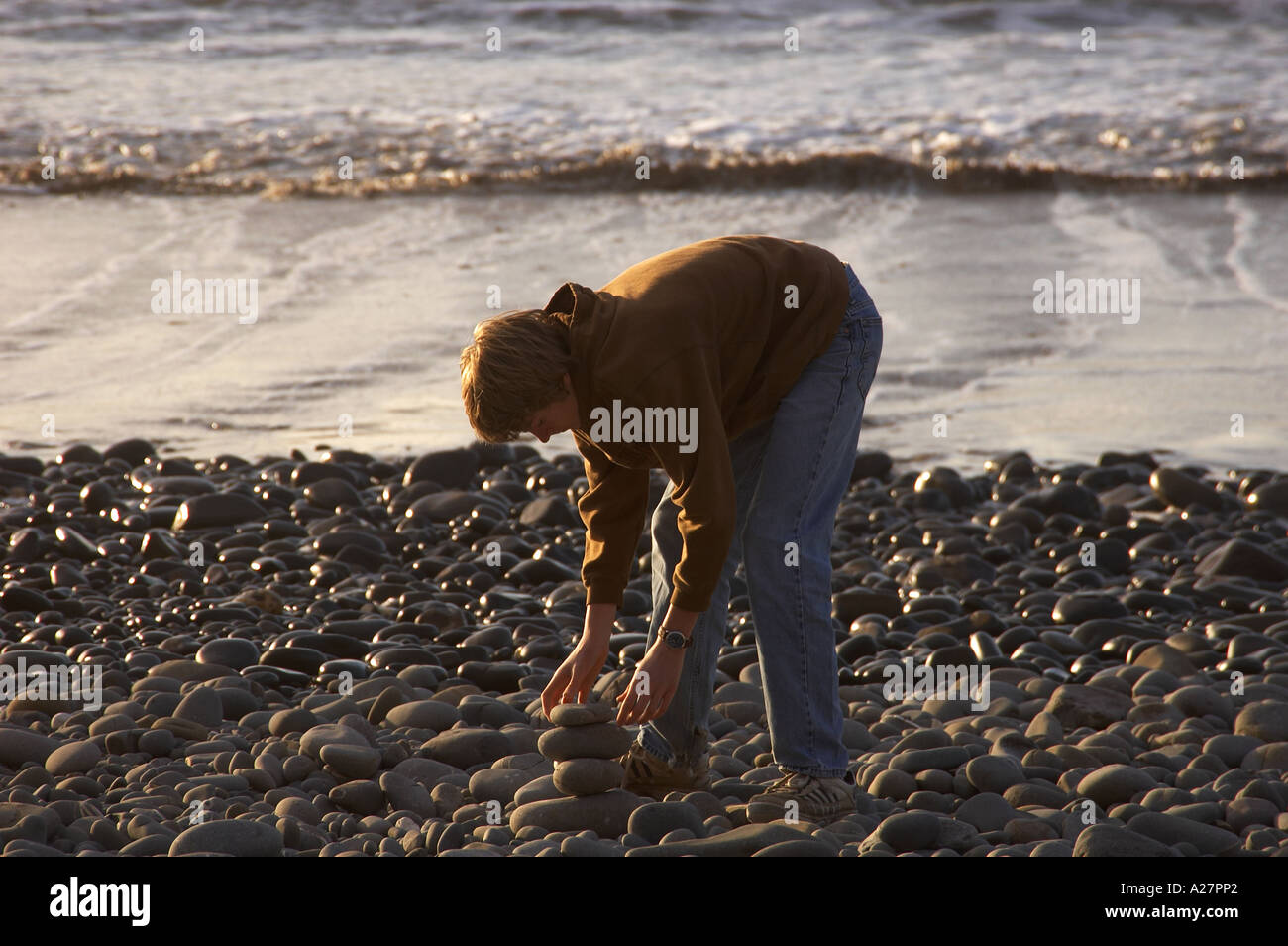 Boy building a stone pile on beach Stock Photo - Alamy