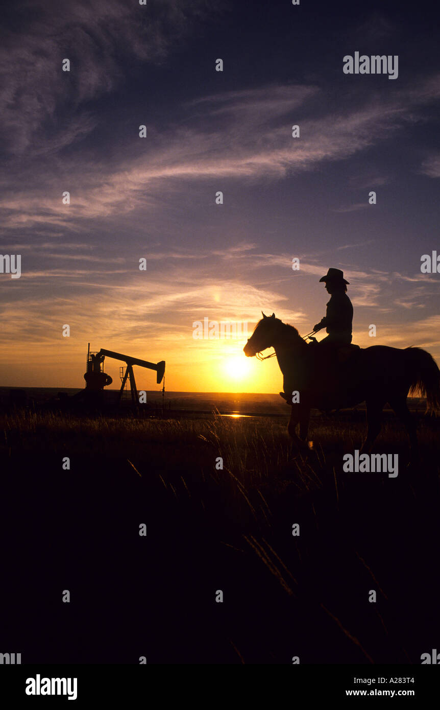 A silhouetted cowboy and oil well at sunset in North Dakota Stock Photo ...