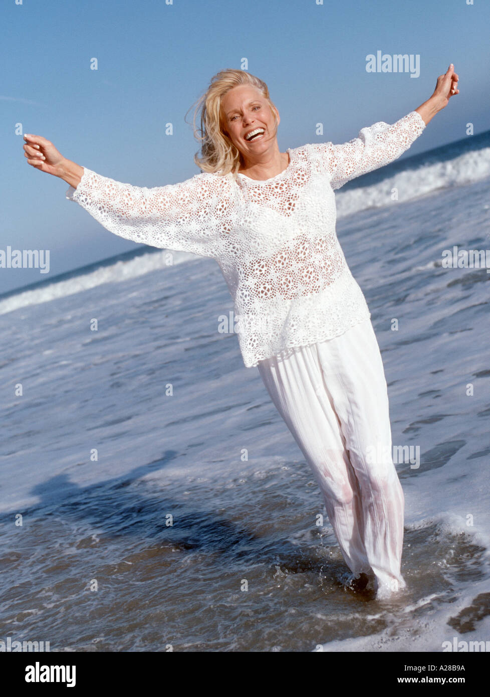 Mature active and healthy woman frolicing in surf at beach Stock Photo ...