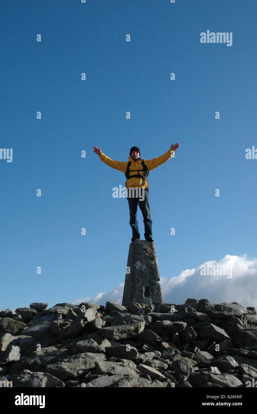Hiker standing on top of trig point waving Stock Photo - Alamy