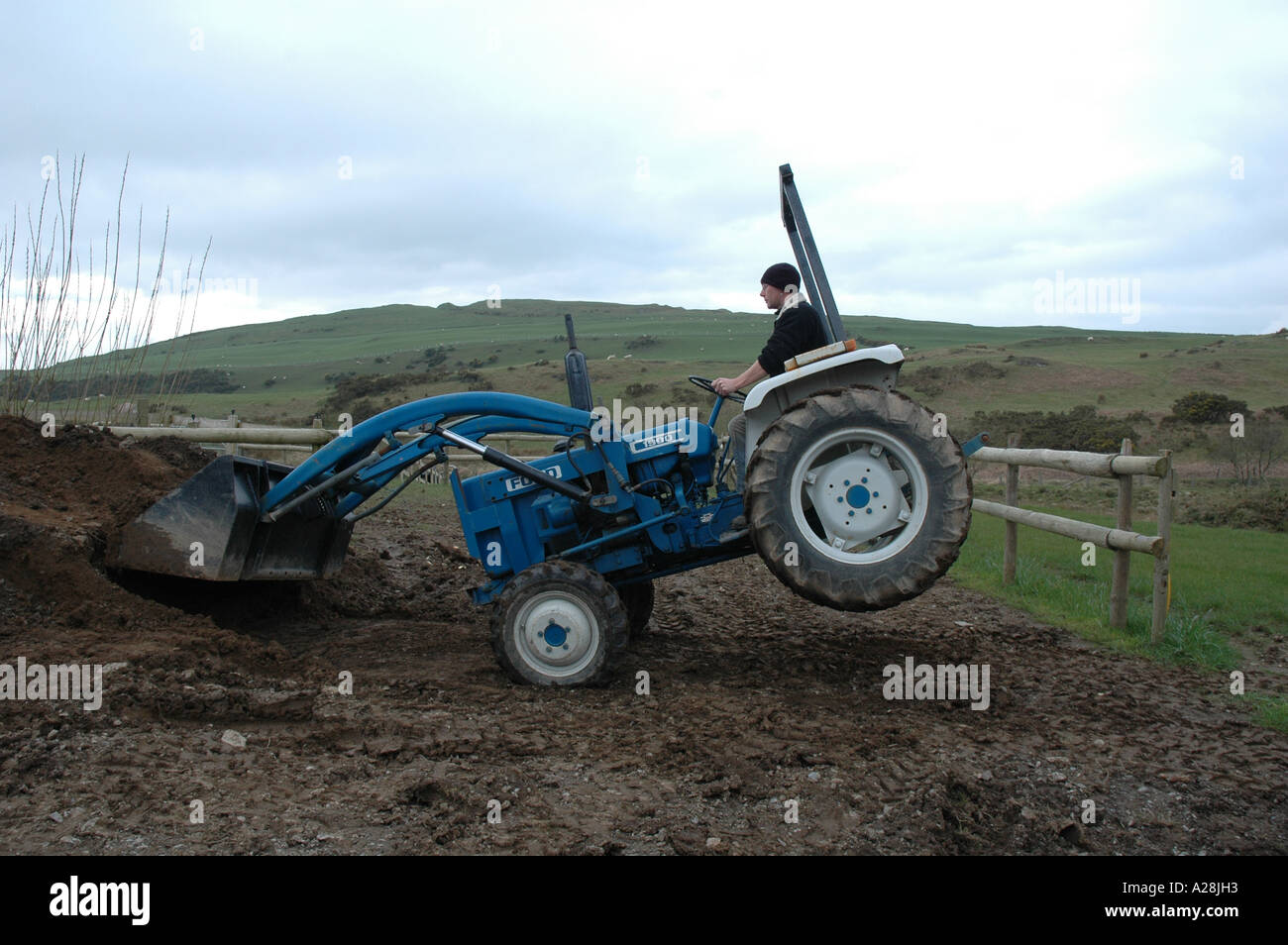 Tractor with back wheels off the ground trying to lift a heavy weight ...