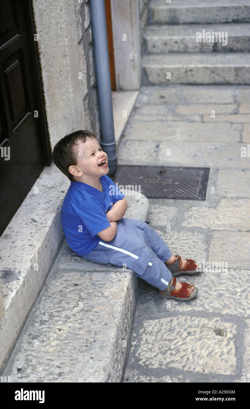 a young boy sat on a step Stock Photo - Alamy