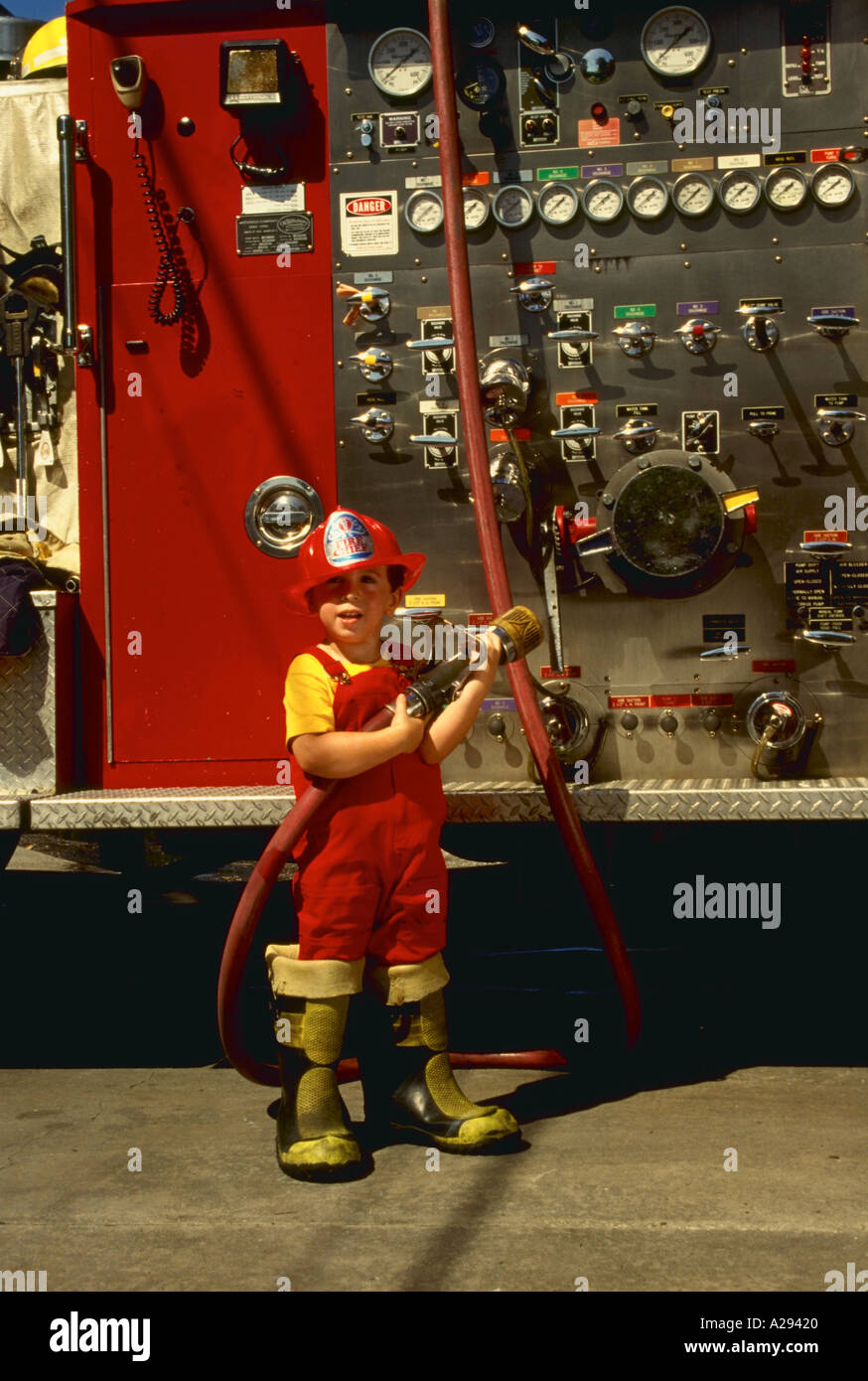 Yound child standing beside fire truck with fire hose Stock Photo - Alamy