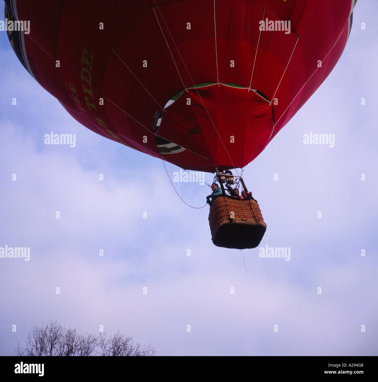 Red hot air balloon taking off with people basket Stock Photo - Alamy