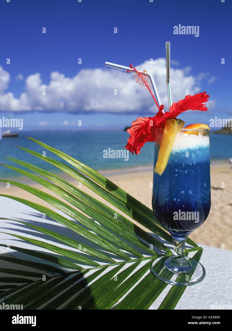 A blue cocktail decorated with fruit and hibiscus flower against a ...