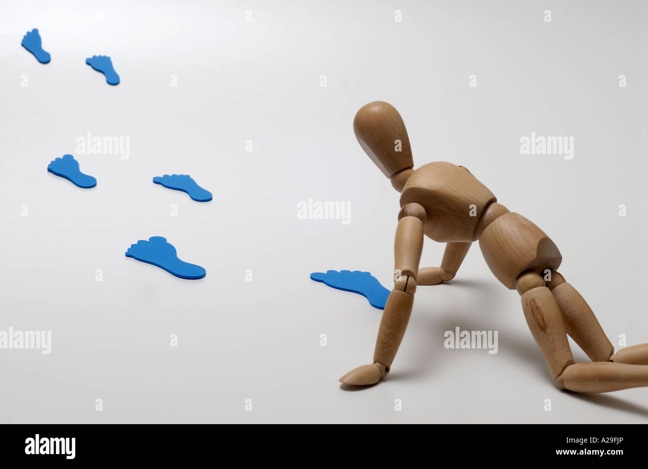 A wooden man inspects blue footprints Symbolic of loneliness finding ...