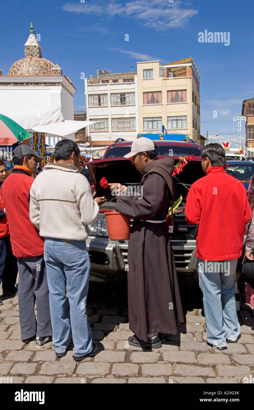 A priest in the process of blessing a vehicle at the entrance to the ...