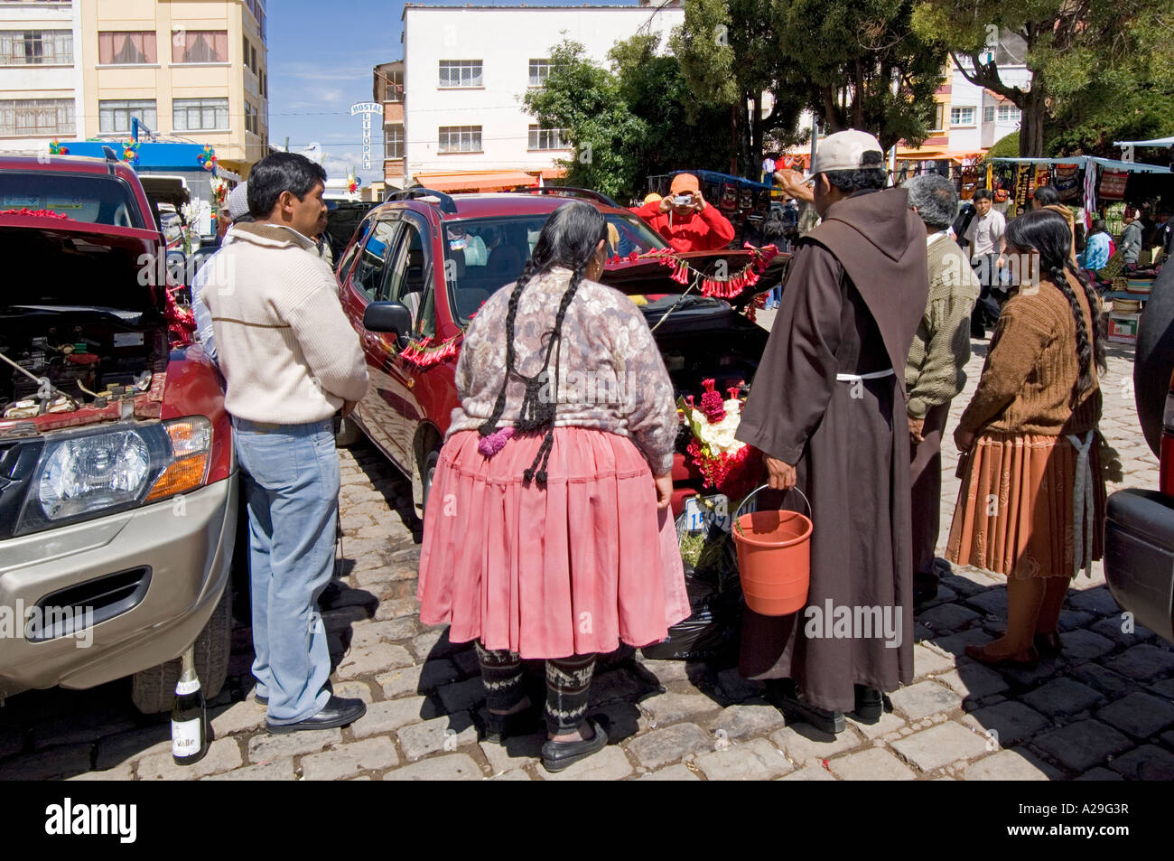 A priest in the process of blessing a vehicle at the entrance to the ...