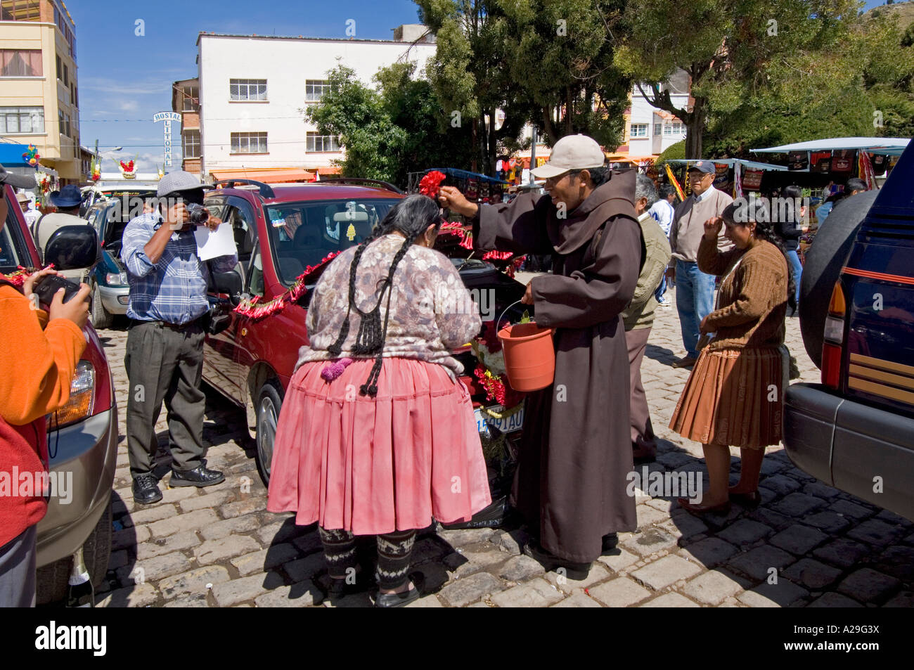 A priest in the process of blessing a vehicle at the entrance to the ...