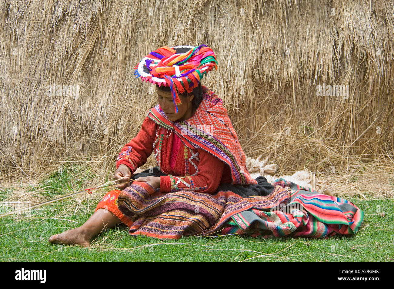 A Peruvian woman dressed in traditional clothes demonstrating fabric ...