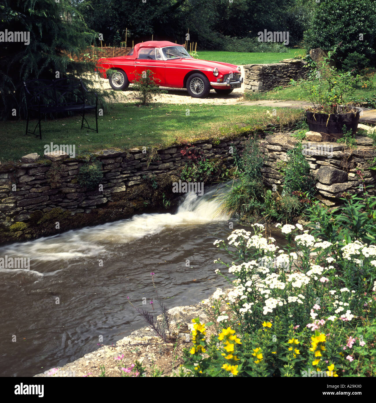Classic sports car beside mill race stream garden feature Stock Photo ...