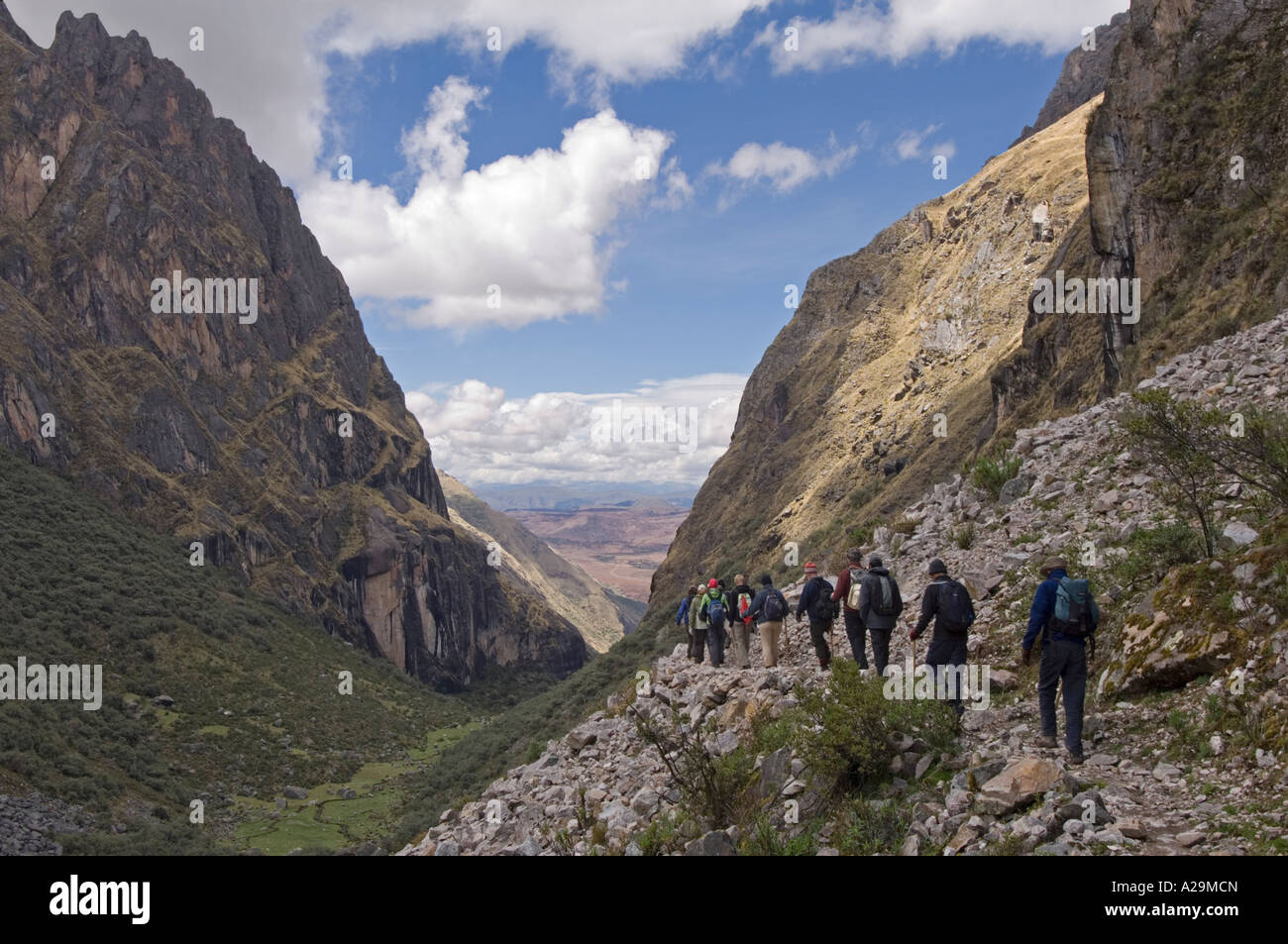 A group of tourists and guides trekking through the rugged scenery of ...