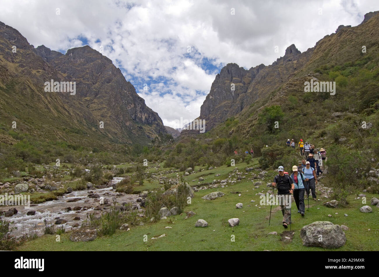A group of tourists and guides trekking through the rugged scenery of ...