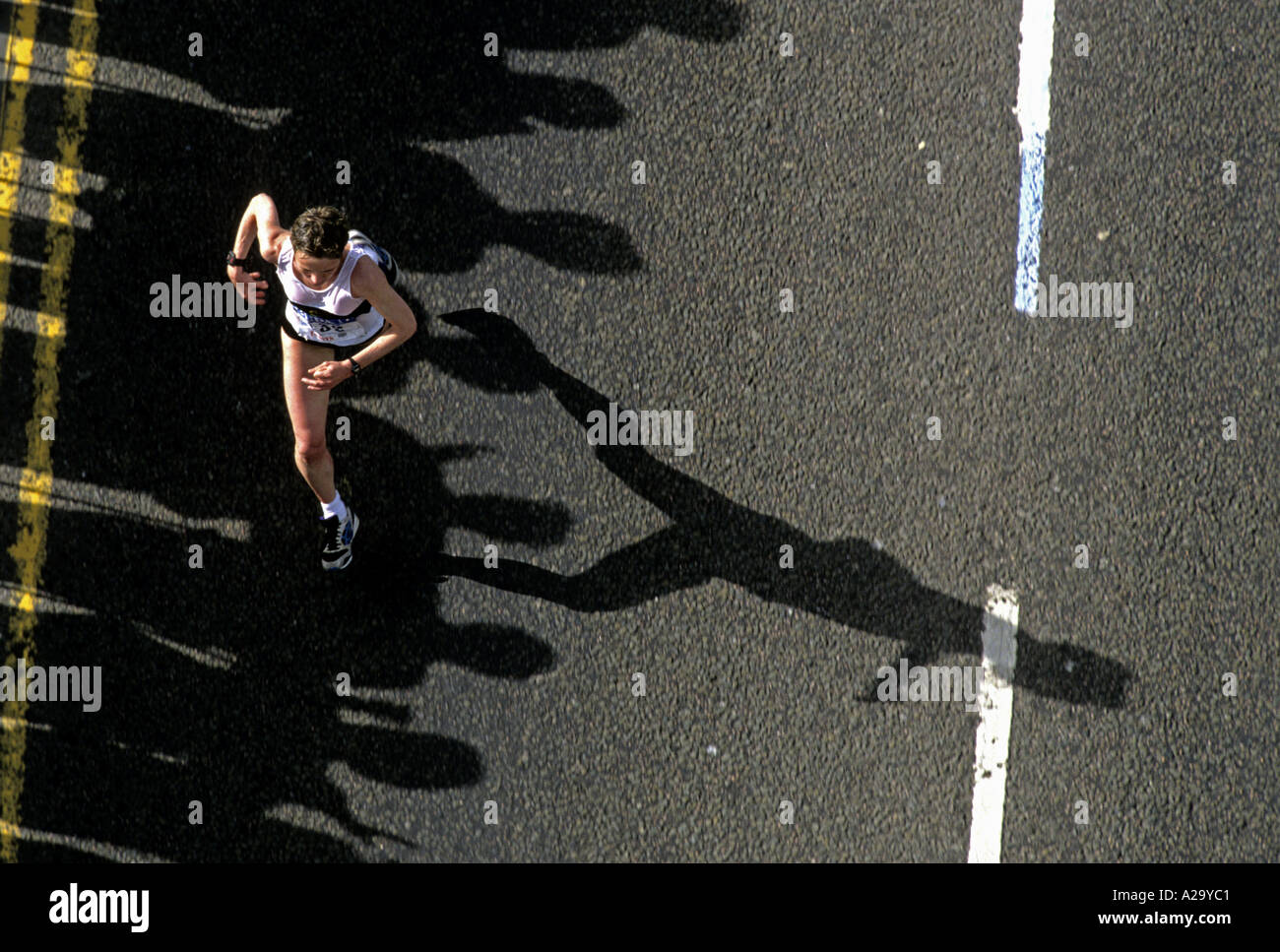 Overhead view of a female runner running through the shadows of ...