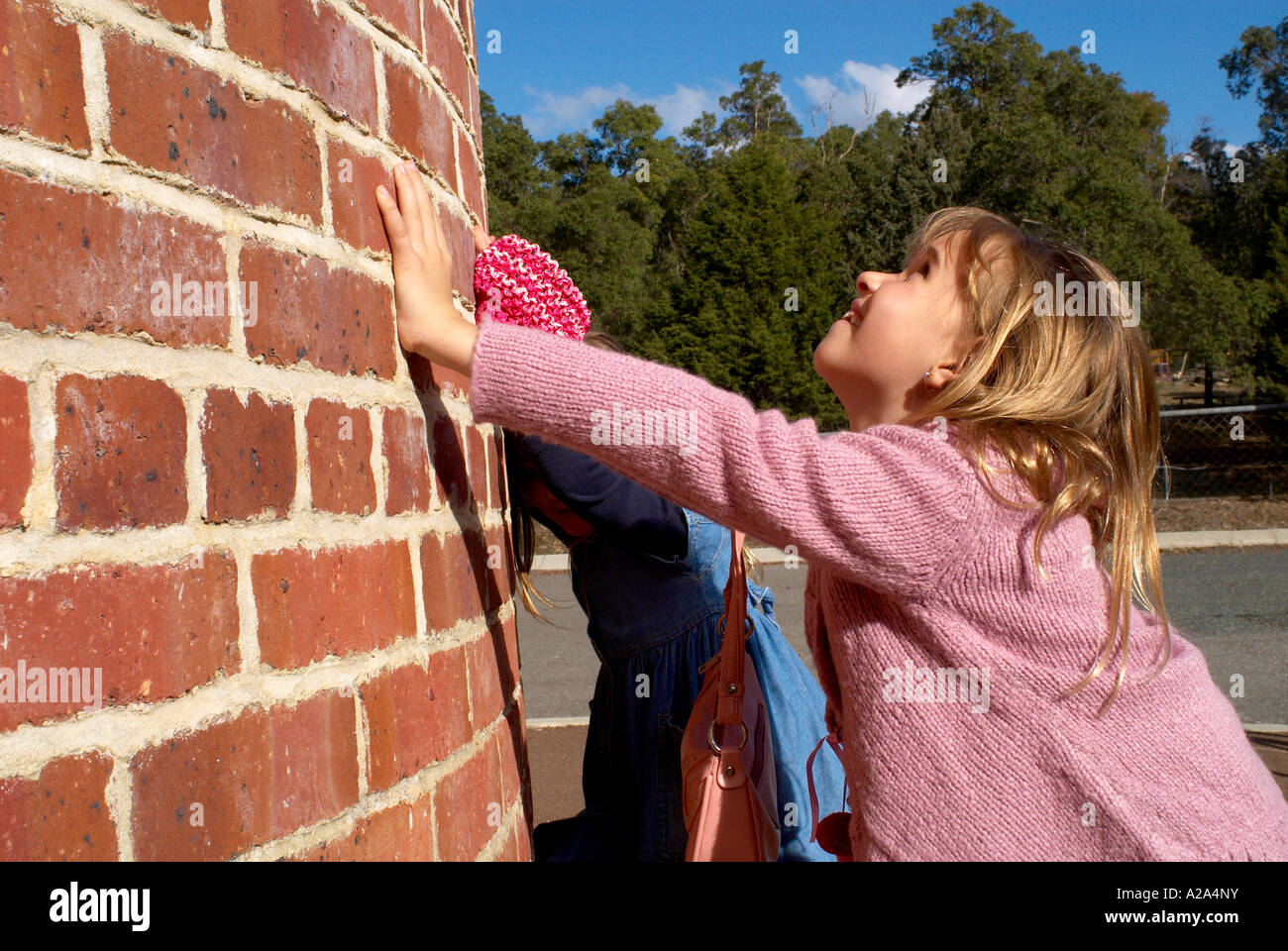 8 year old female child leaning against brick chimney stack, younger ...