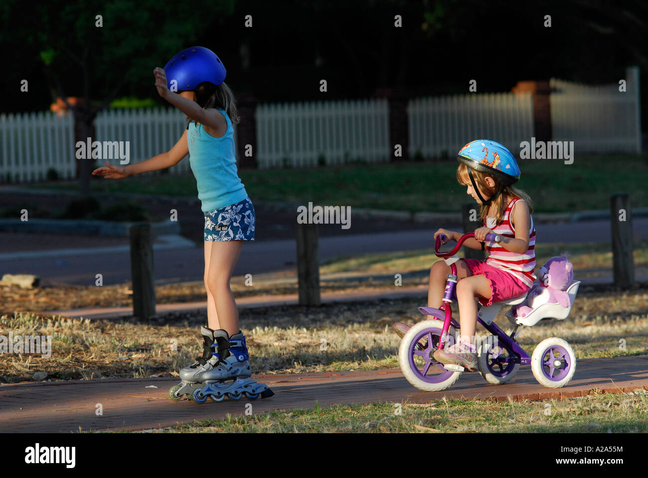one child on inline skates, another riding a tricycle Stock Photo - Alamy