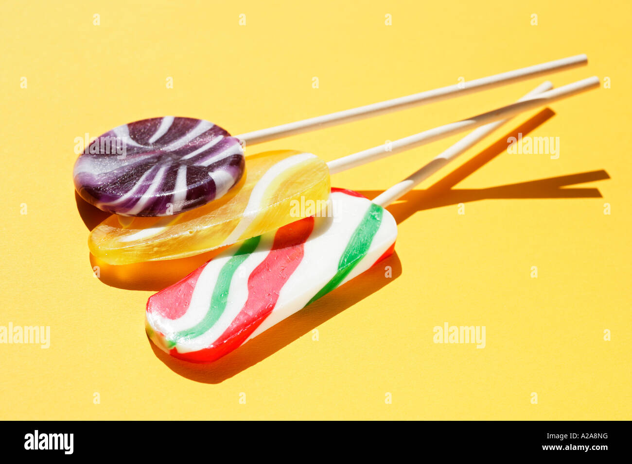 Three lollipops on yellow ground Stock Photo - Alamy