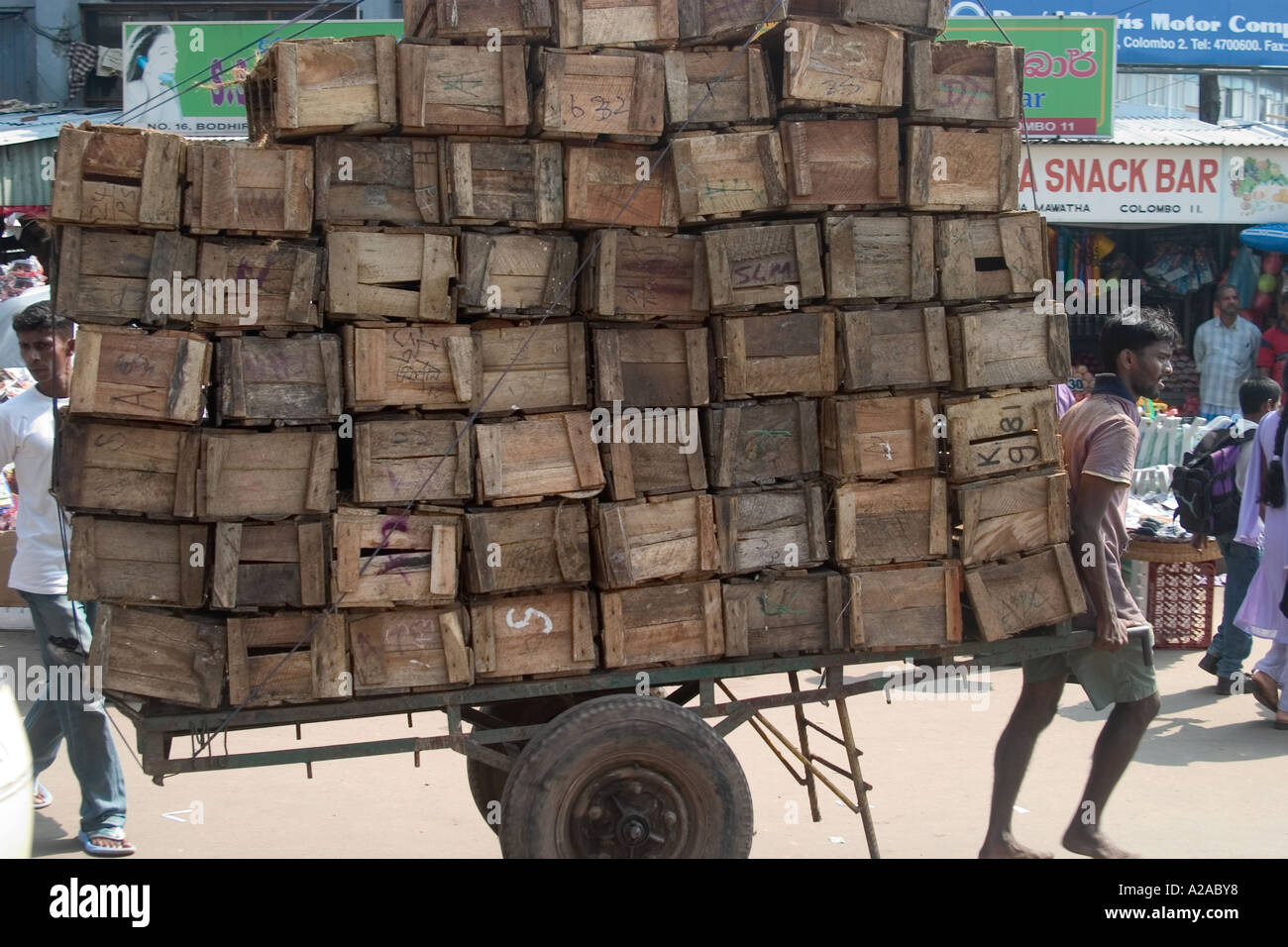 Porter pulling heavy cart loaded with many wooden boxes. The Pettah ...