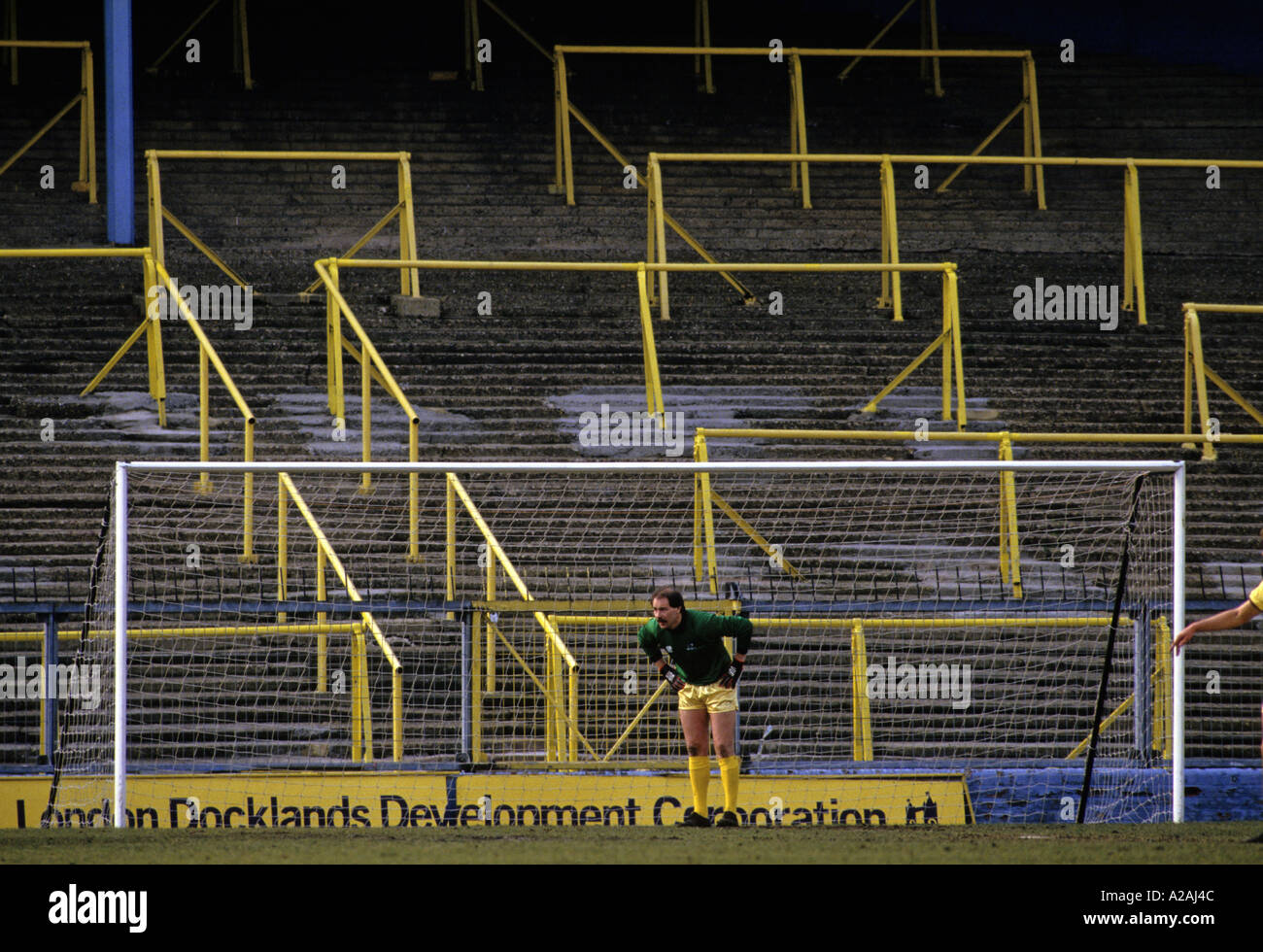 A goalkeeper waiting in his goalmouth with the empty terraces behind ...