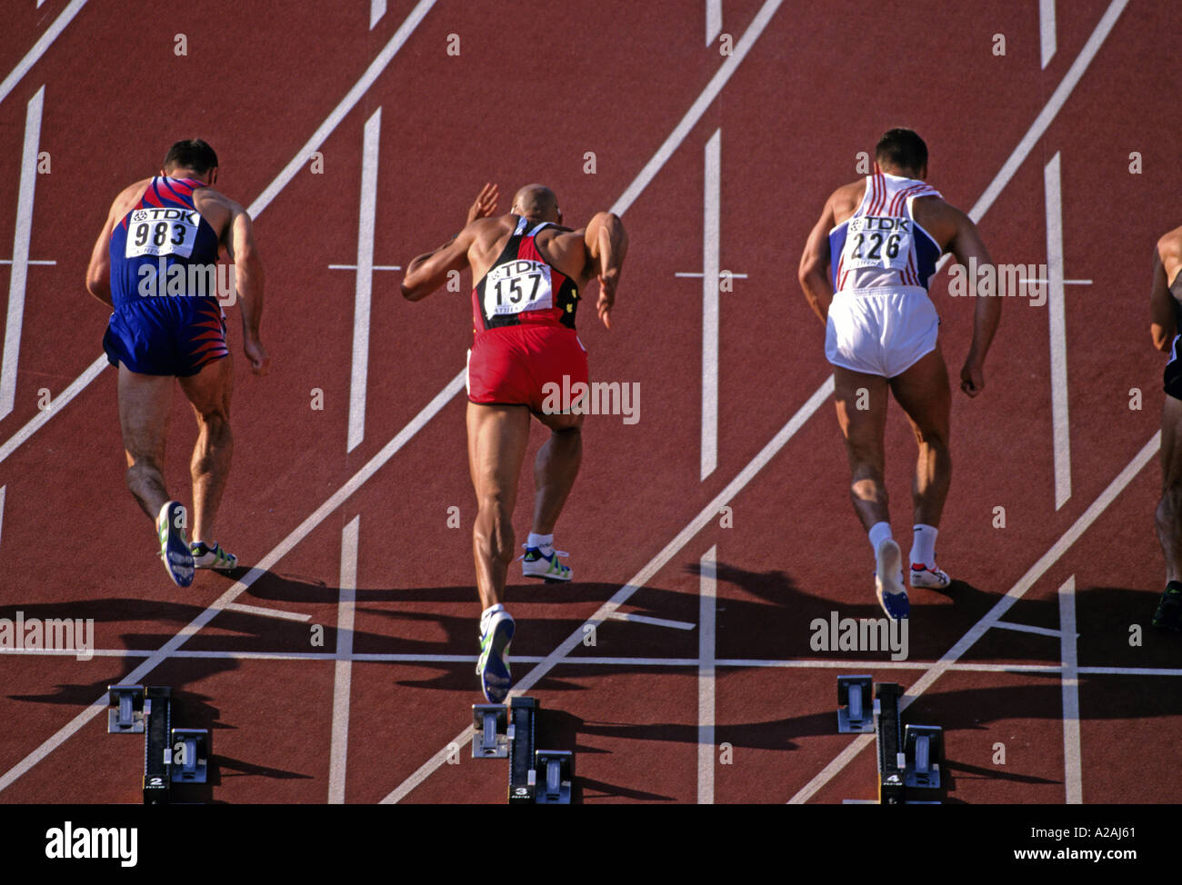 Overhead view of male sprinters pushing off from the starting blocks ...