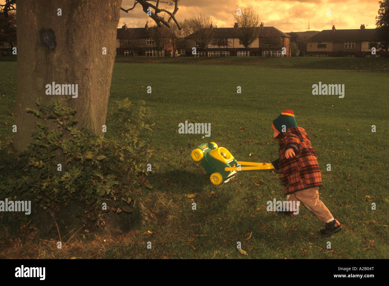 Little Boy With A Toy Lawn Mower,Pretending To Cut The Grass ,In A Park ...