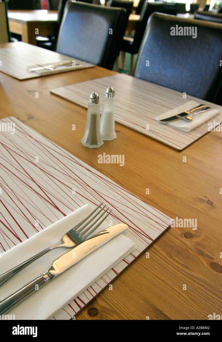Modern wooden restaurant table showing knives, forks and condiment set ...