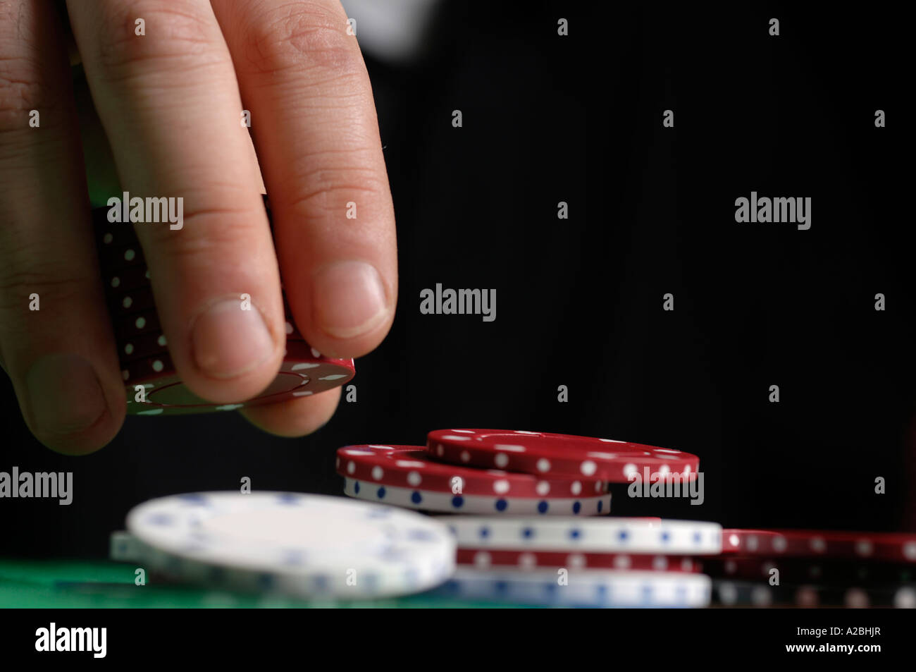 Man putting chips into pot at card table Stock Photo - Alamy