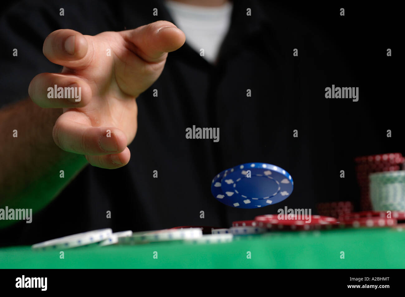 Man throwing chips into pot at card table Stock Photo - Alamy