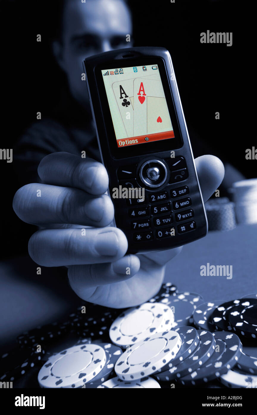 Young man showing pair of aces on mobile phone Stock Photo - Alamy