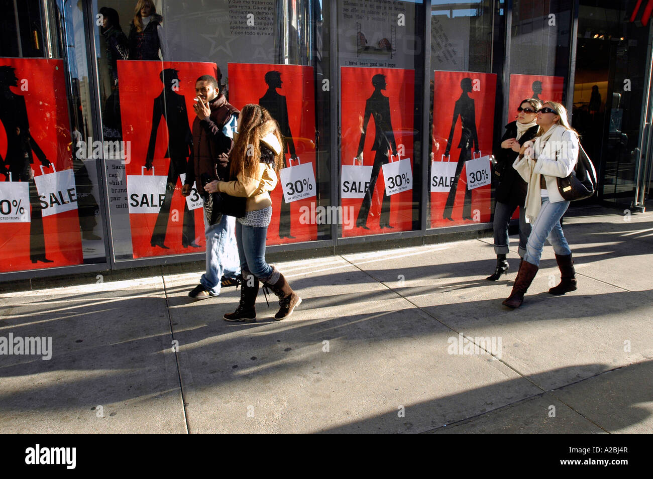 Shoppers pass by the sales signs in the window of an H M Department ...
