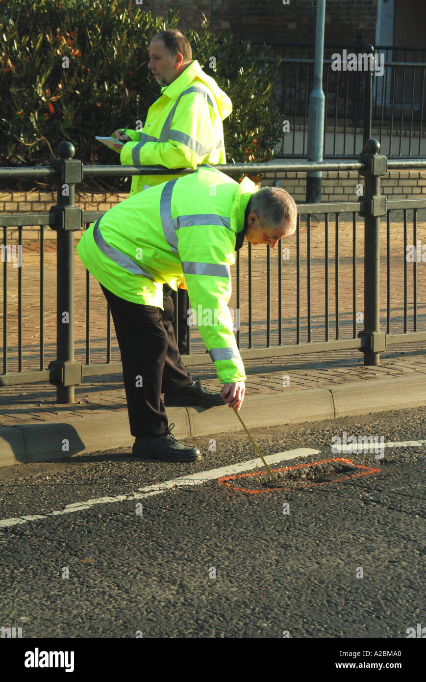 Two highway authority pot hole inspectors surveying & spray painting ...