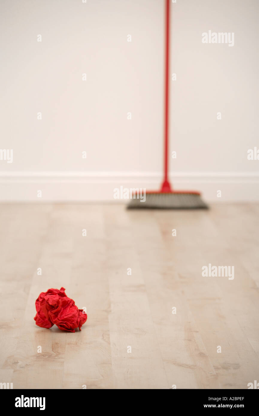 CRUMPLED RED WASTE PAPER ON WOODEN OFFICE FLOOR WITH RED SWEEPING BRUSH ...
