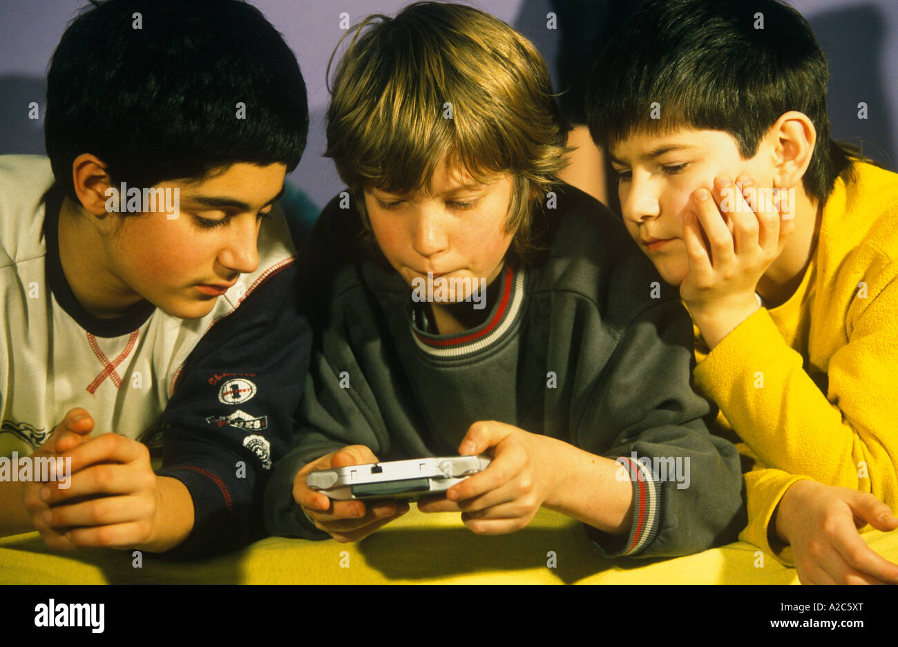a young boy is playing with his gameboy while his two friends are ...
