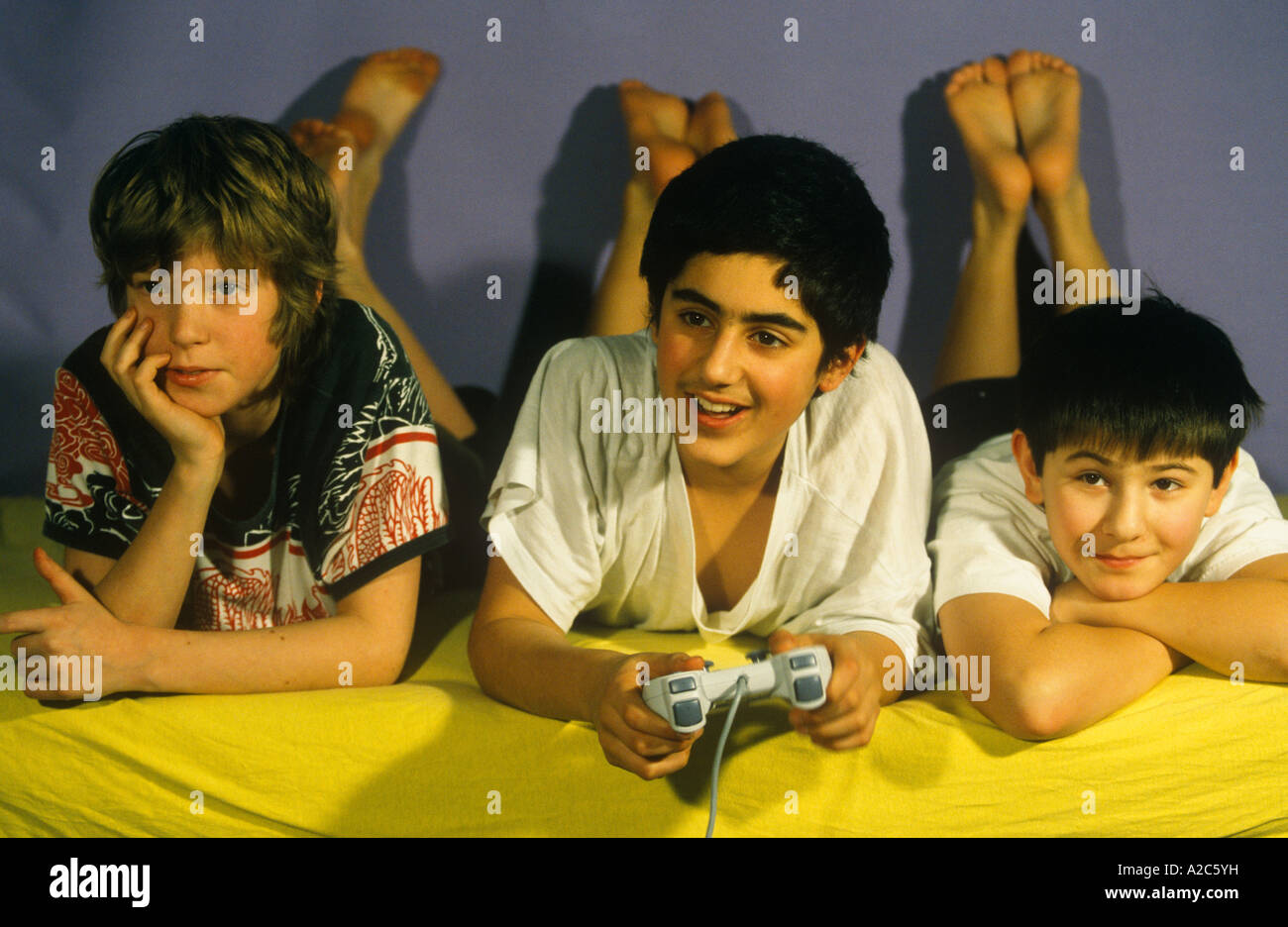 a young boy is playing with his playstation while his two friends are ...