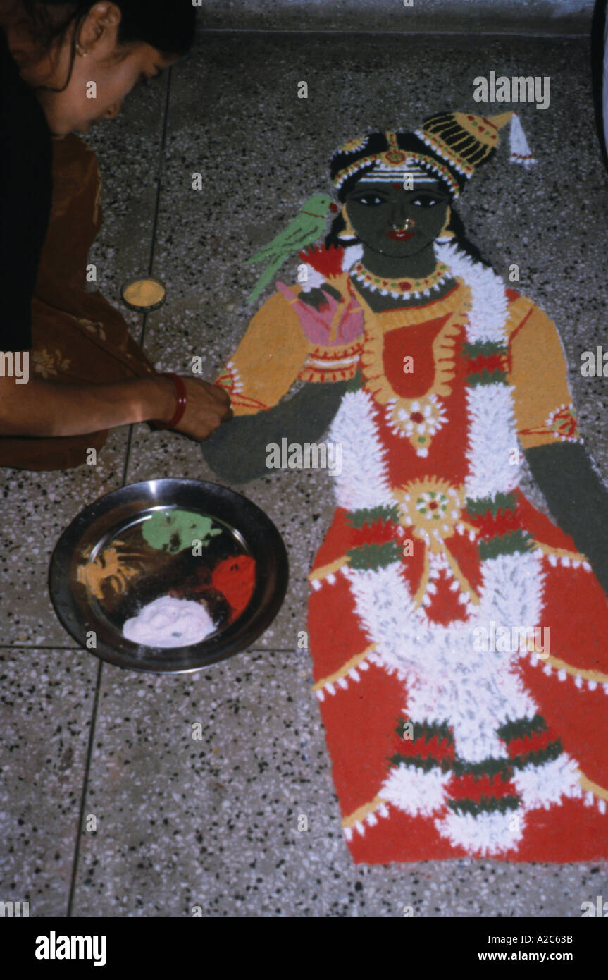 A girl draws a rangoli outside her house. Art designs are a custom made ...