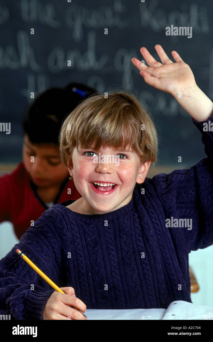 Excited young elementary aged boy raising his hand to answer a question ...