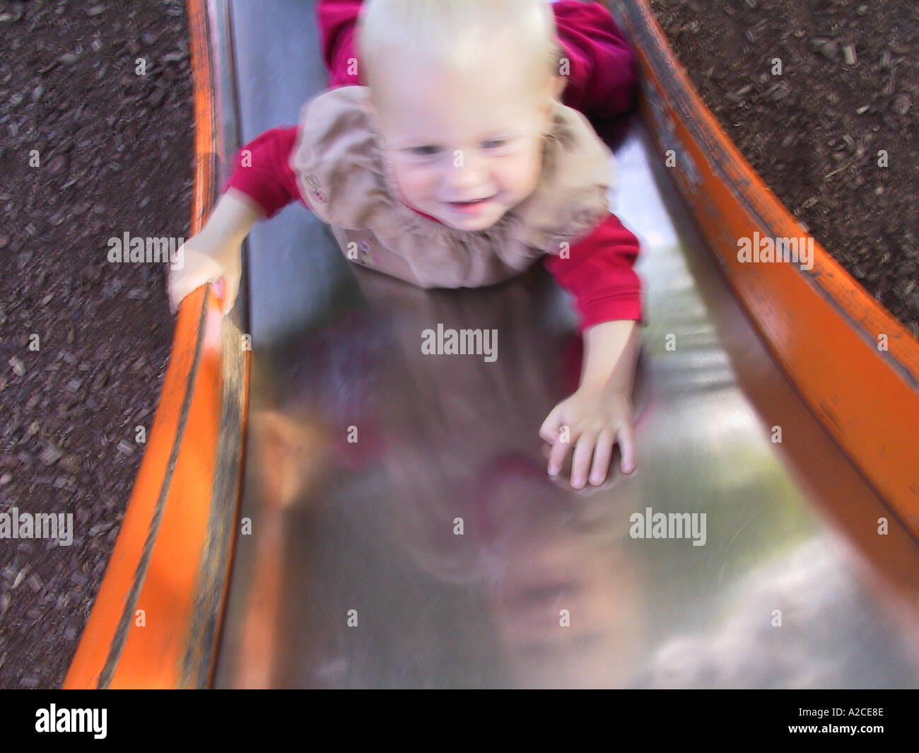 A one year old girl sliding backwards down a slide Stock Photo - Alamy