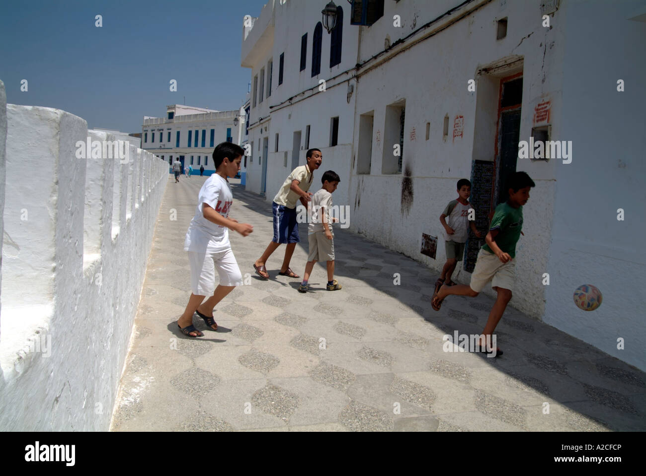 Children playing football in a Medina street by the whitewashed ...