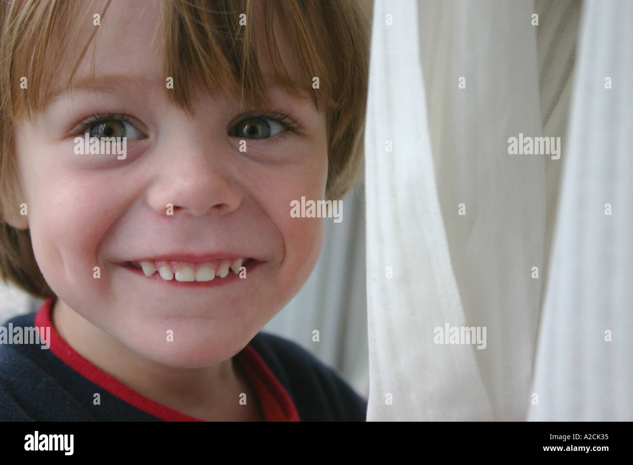 two year old boy smiling next to curtains Stock Photo - Alamy